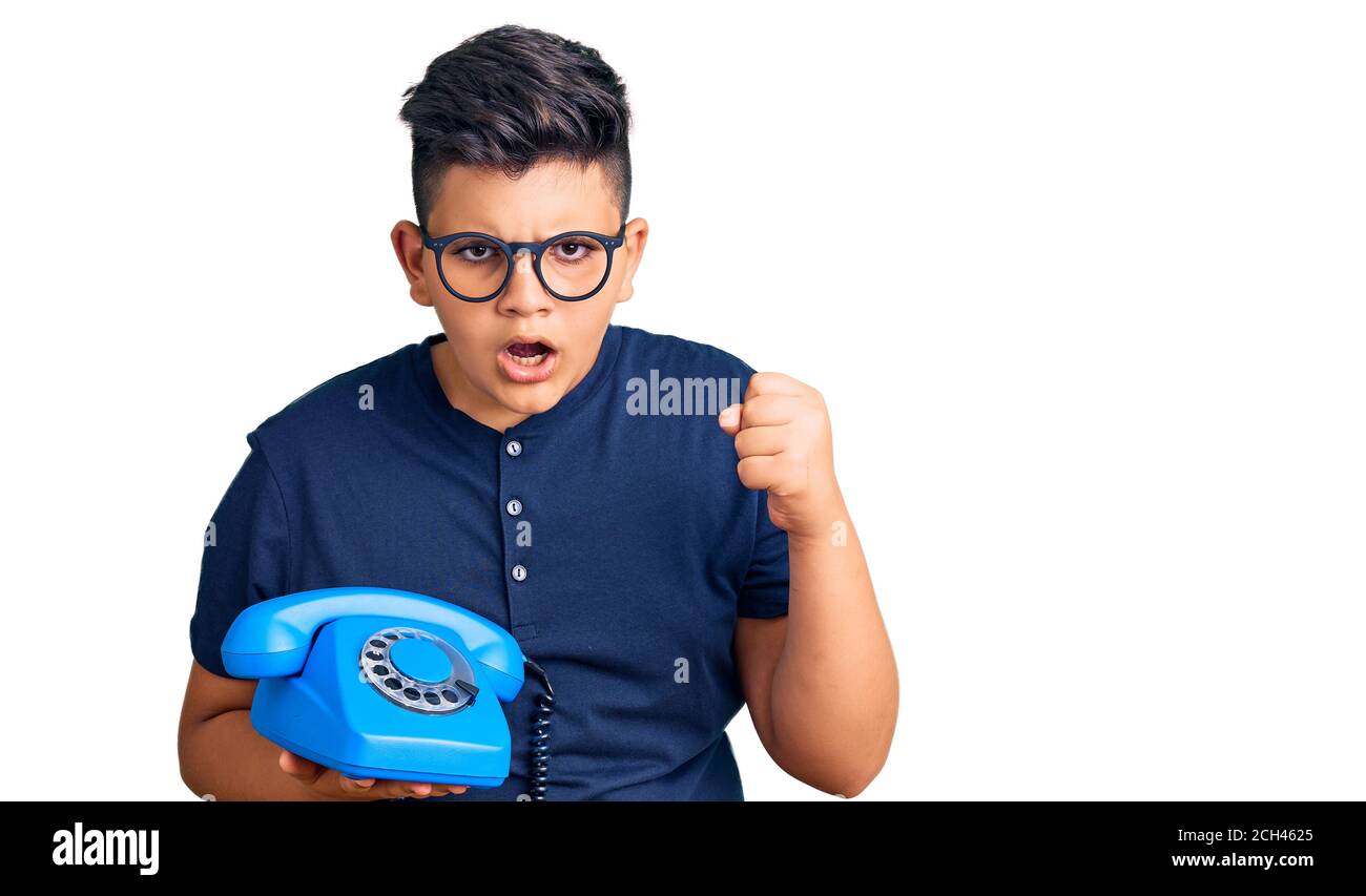 Little boy kid using vintage telephone annoyed and frustrated shouting ...