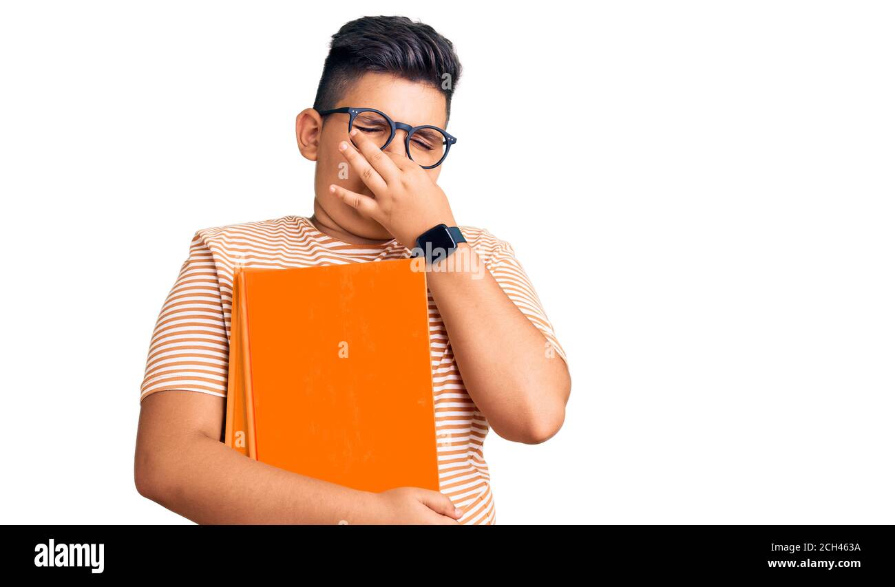 Little boy kid holding book wearing glasses smelling something stinky ...