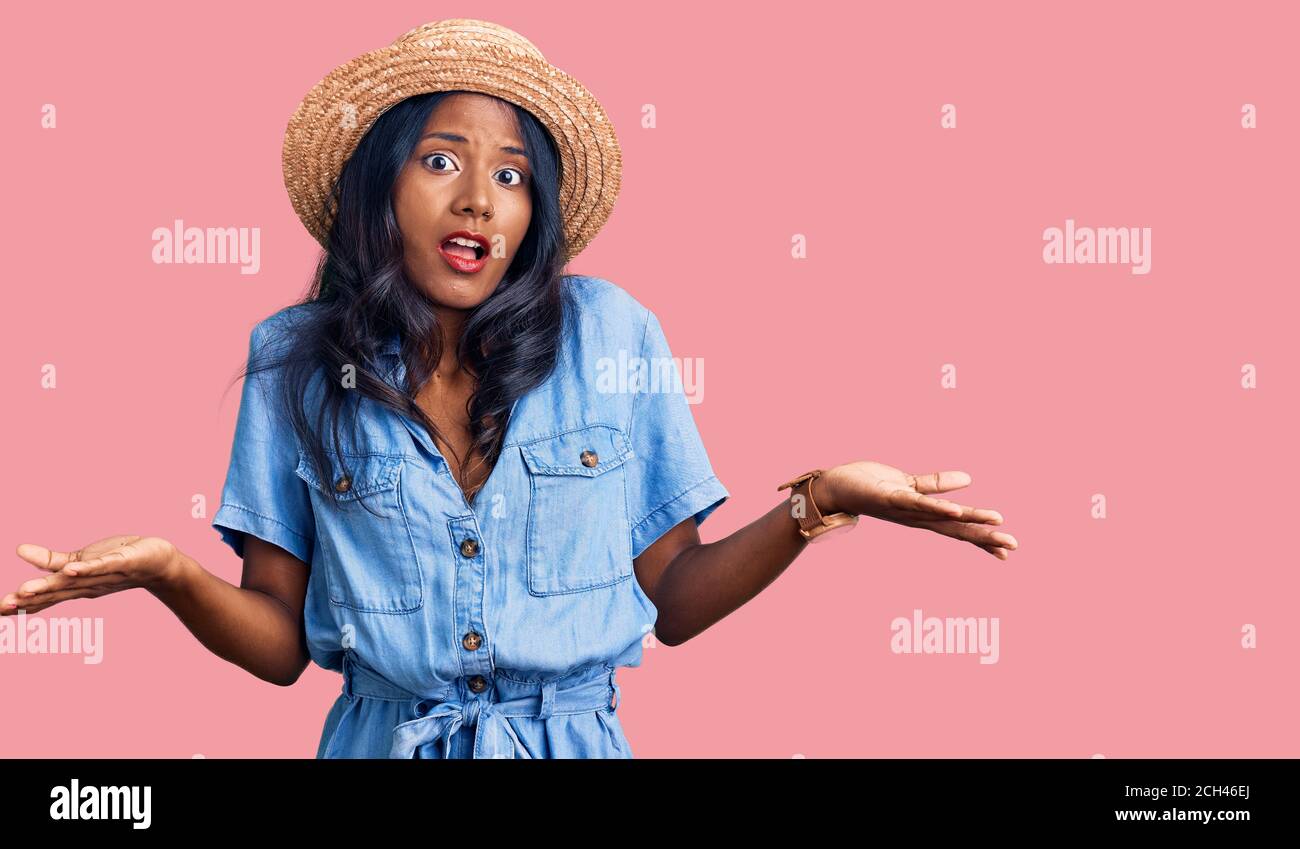 Young indian girl wearing summer hat clueless and confused with open ...