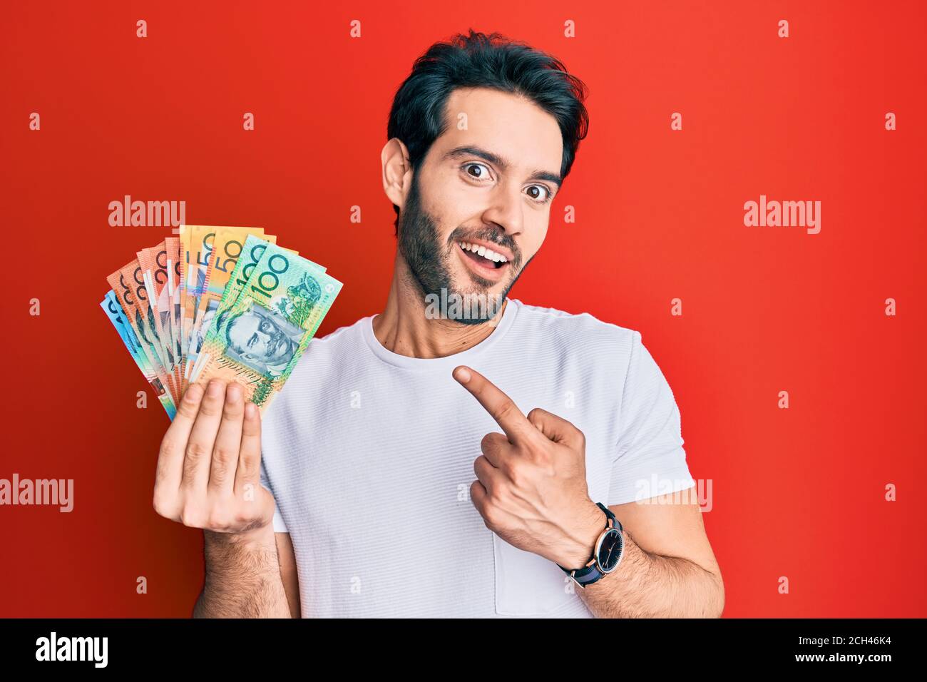 Young hispanic man holding australian dollars smiling happy pointing ...