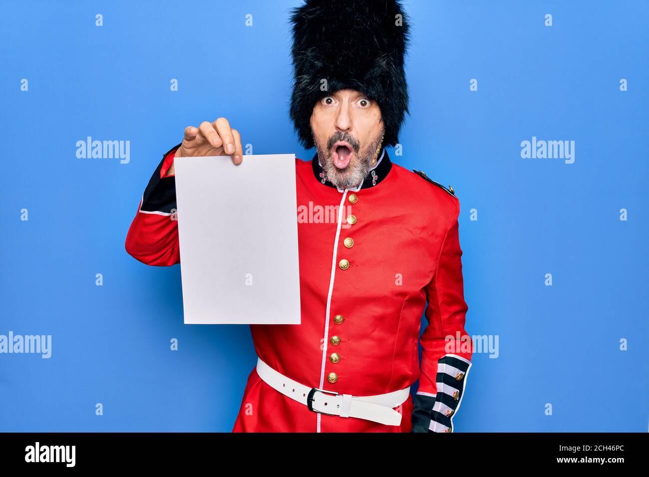 Middle age handsome wales guard man wearing traditional uniform holding ...