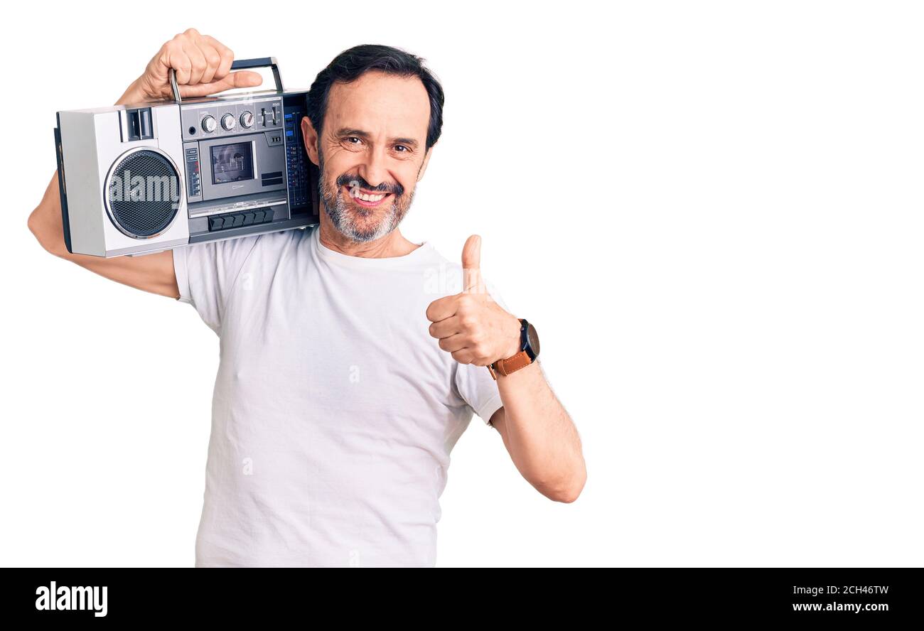 Middle age handsome man listening to music using vintage boombox ...