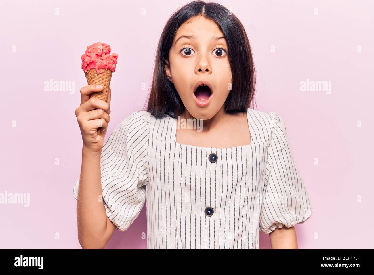 Beautiful child girl holding ice cream scared and amazed with open ...