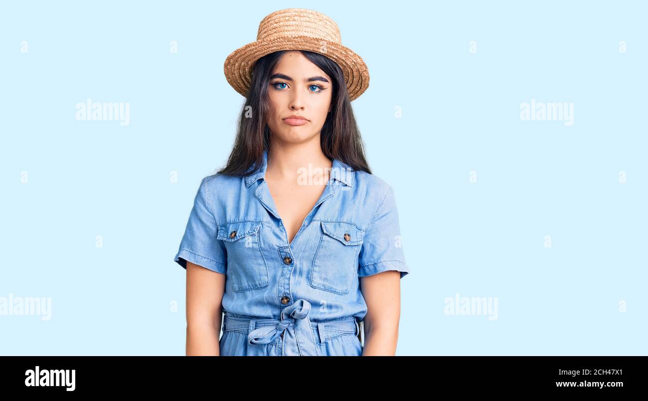 Brunette teenager girl wearing summer hat relaxed with serious ...