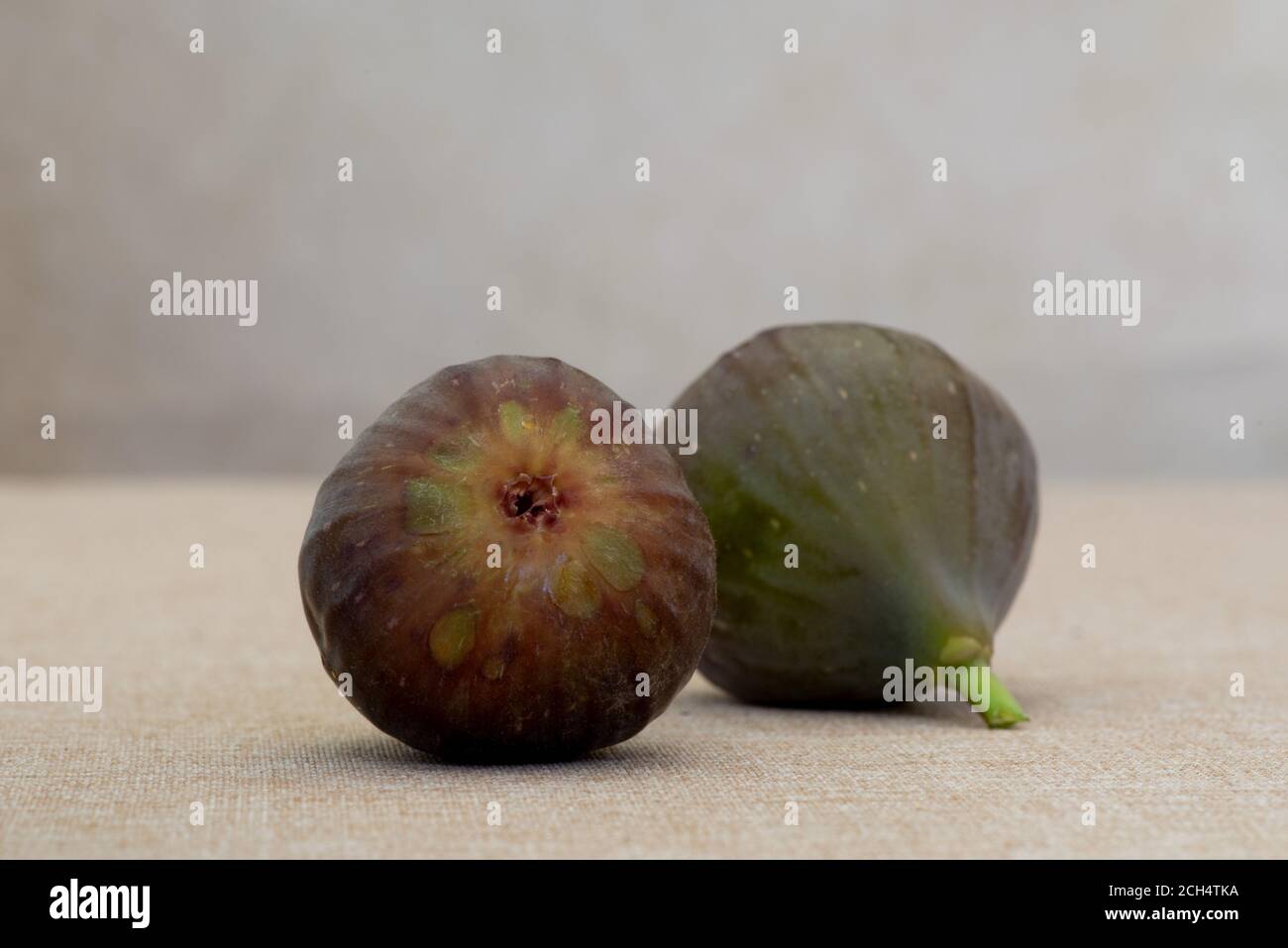 Two brown turkey figs side-by-side on tan background viewed from the ...