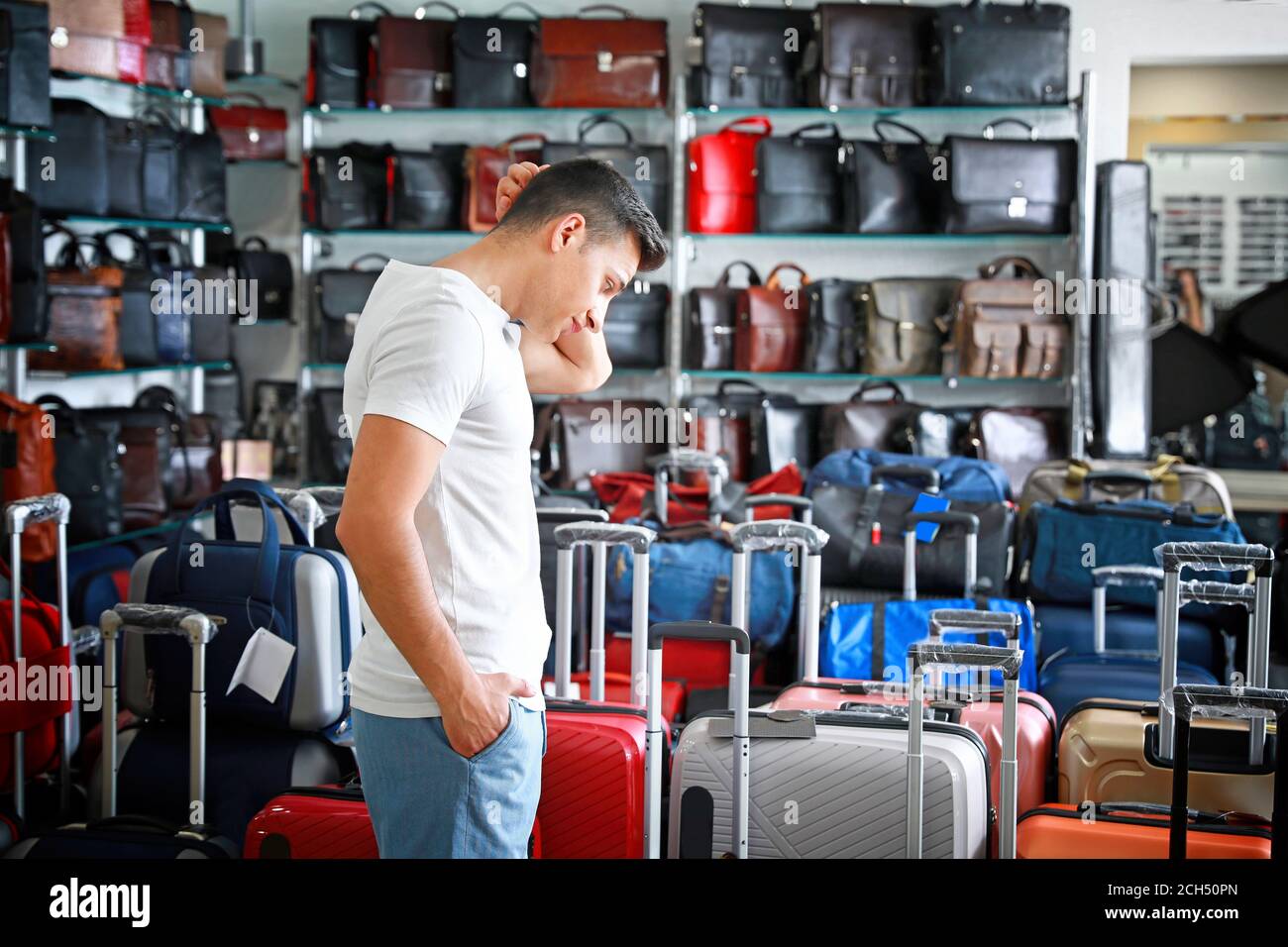 Man choosing suitcase in modern bag store Stock Photo - Alamy