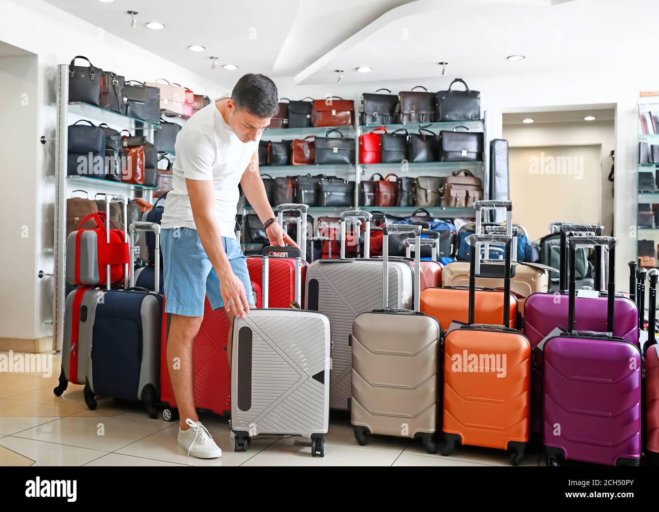 Man choosing suitcase in modern bag store Stock Photo - Alamy