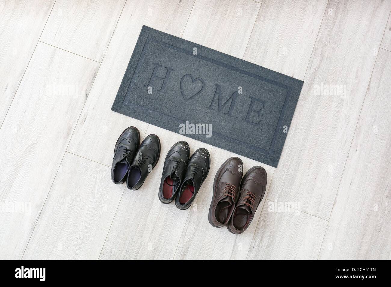 Door mat with shoes on floor in hallway Stock Photo - Alamy