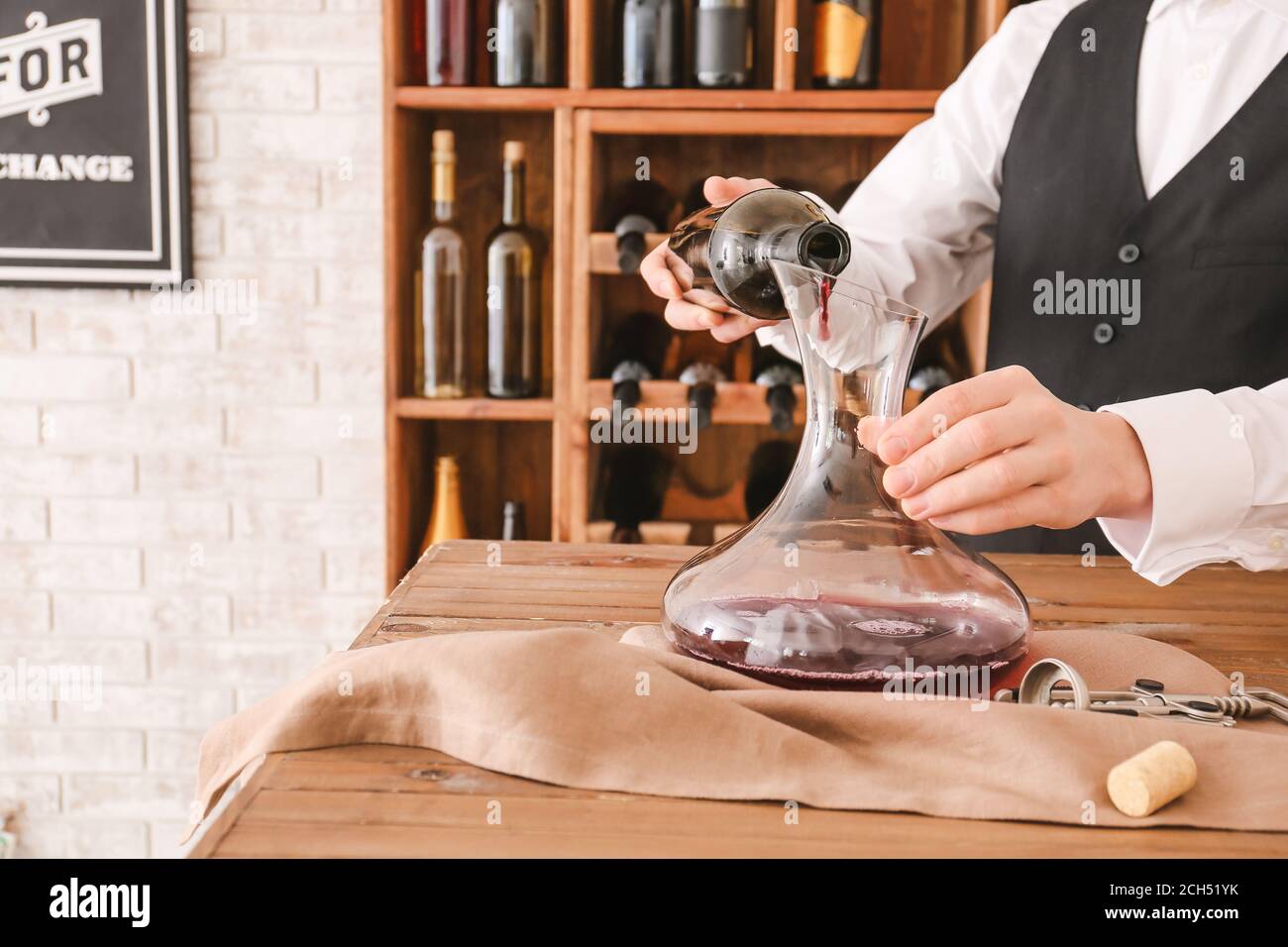 Sommelier pouring wine from bottle into decanter in cellar Stock Photo ...