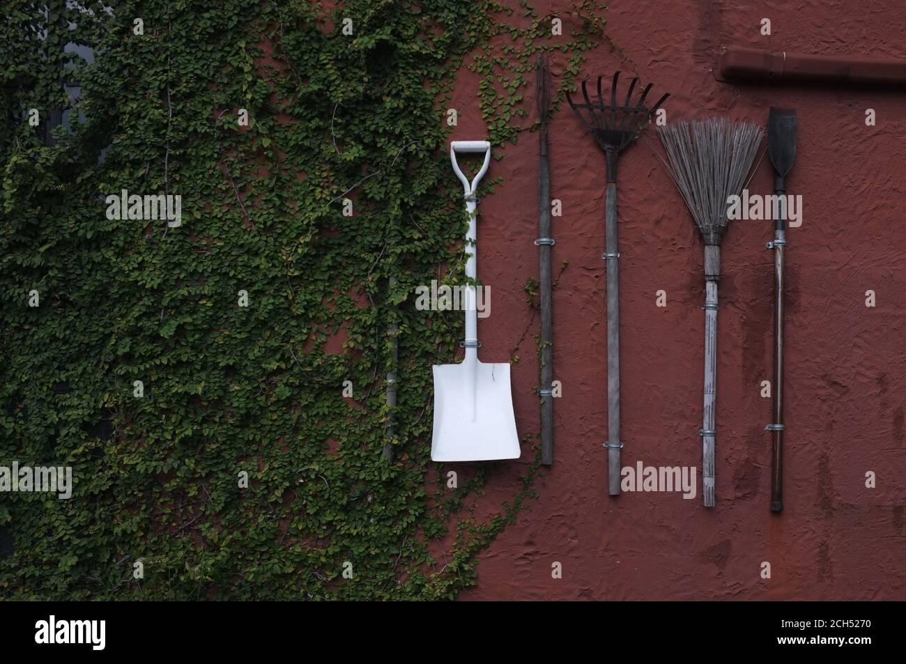 The gardening tools hanging on red cement wall Stock Photo - Alamy