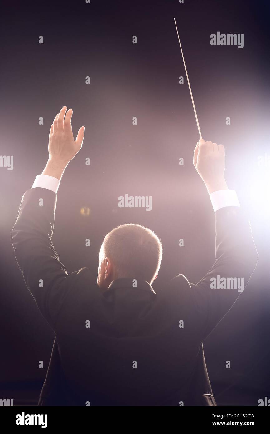 Male conductor on dark background, back view Stock Photo - Alamy