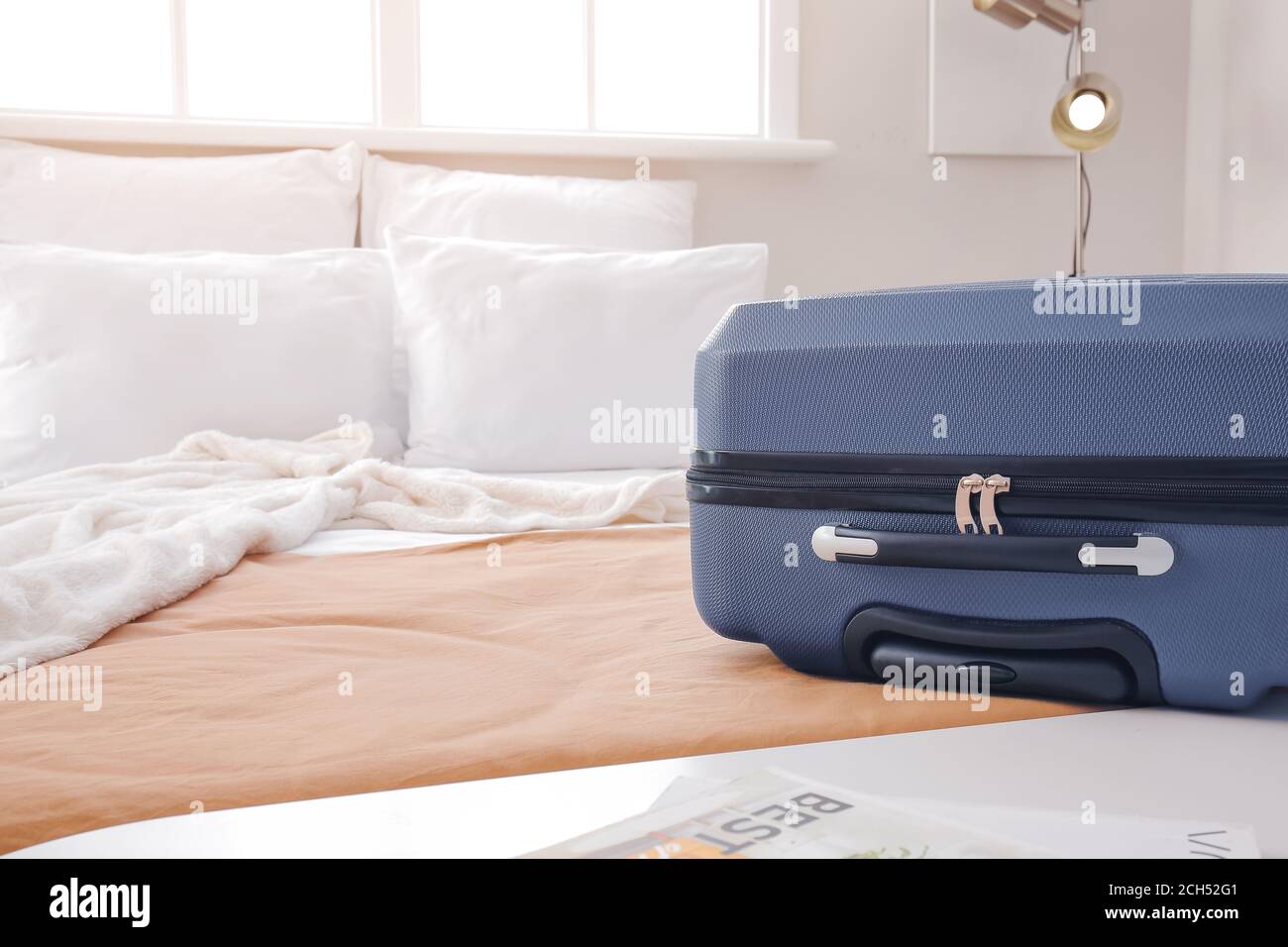 Suitcase on bed in hotel room Stock Photo - Alamy
