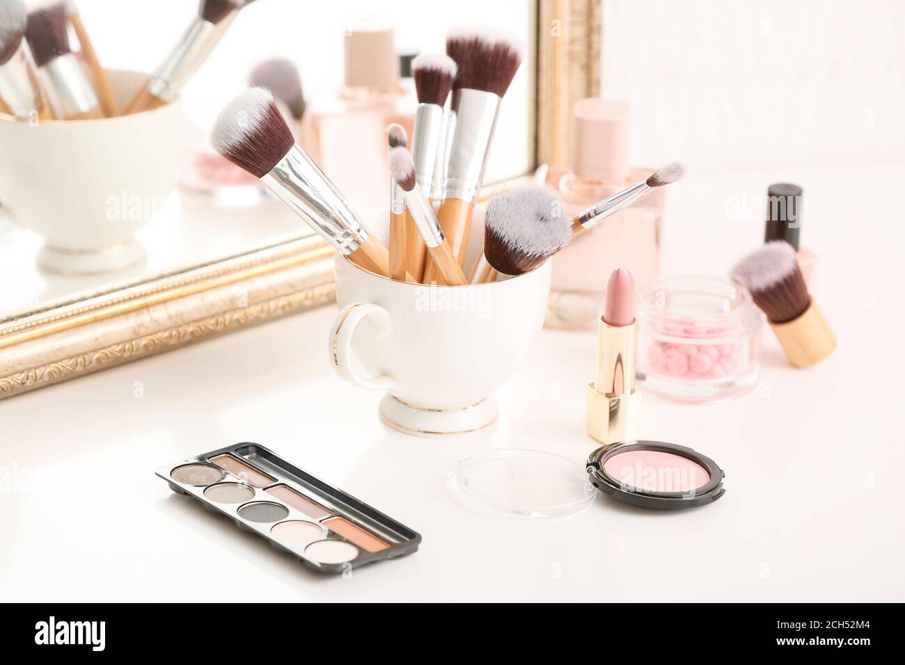 Set of makeup cosmetics with brushes on table Stock Photo - Alamy