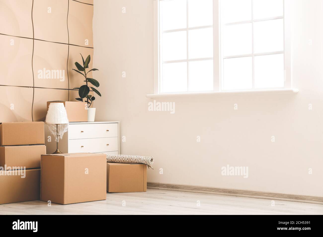 Cardboard boxes with belongings and chest of drawers in new flat on ...