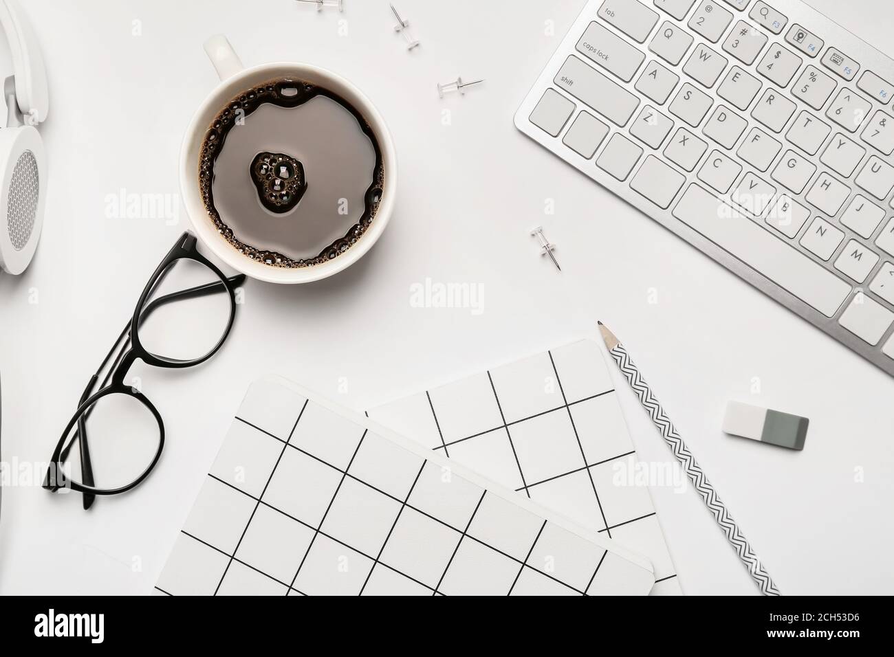 Computer keyboard with stationery and cup of coffee on white background ...