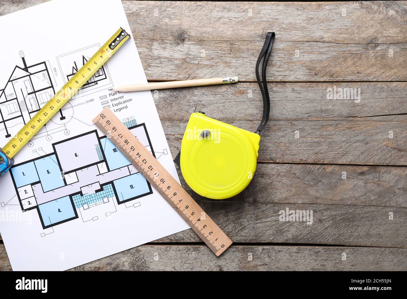 Measuring tapes with blueprint on wooden background Stock Photo - Alamy