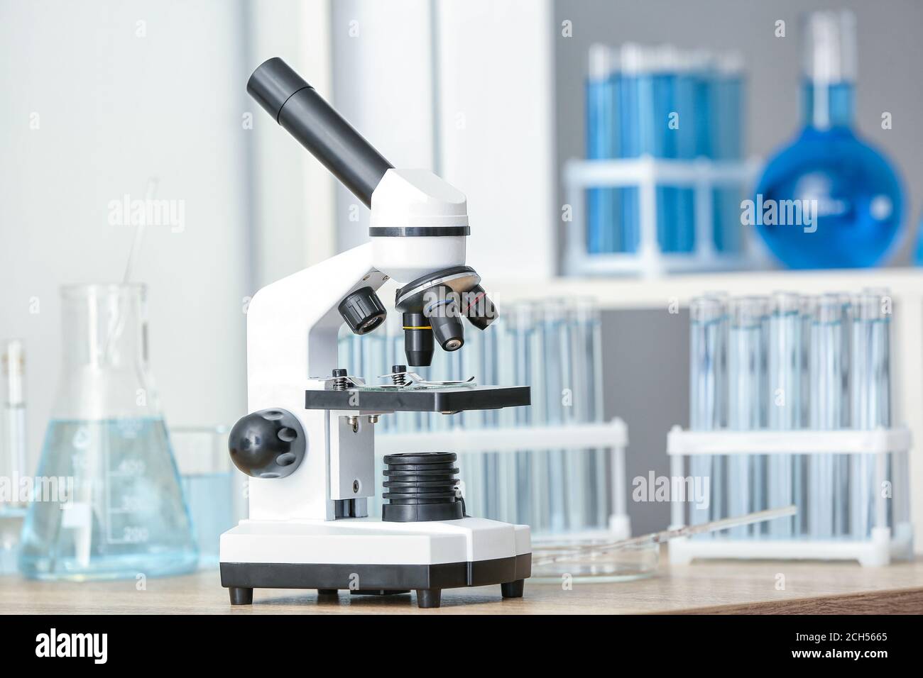 Microscope and glassware on table in laboratory Stock Photo - Alamy