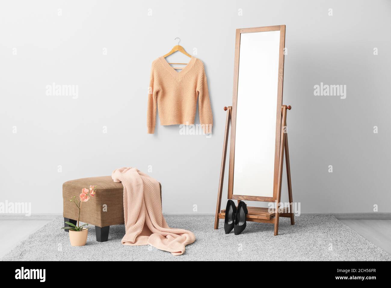 Stylish interior of dressing room with pouf, clothes and mirror Stock ...