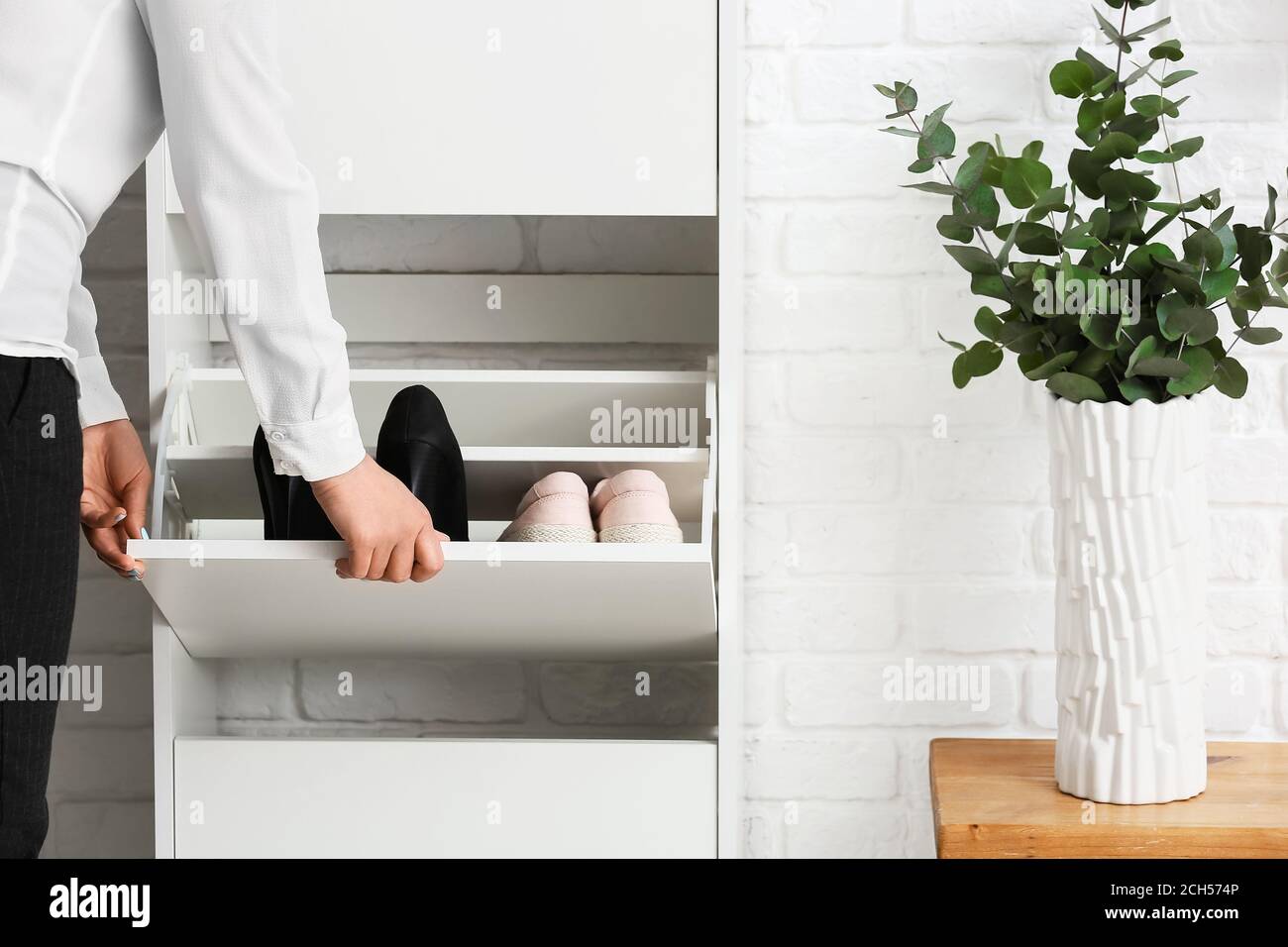 Woman taking shoes from stand in hall Stock Photo - Alamy