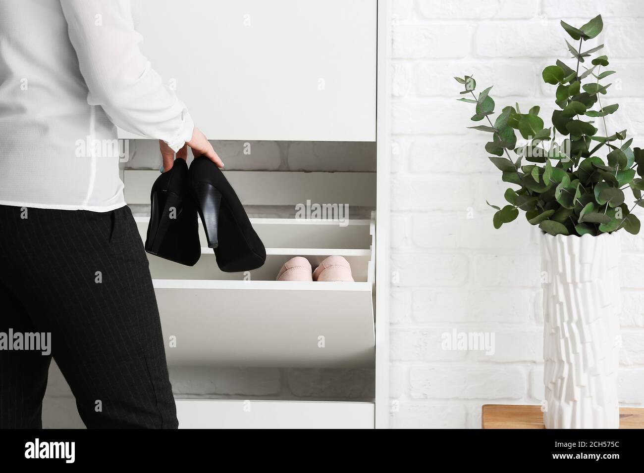 Woman taking shoes from stand in hall Stock Photo - Alamy
