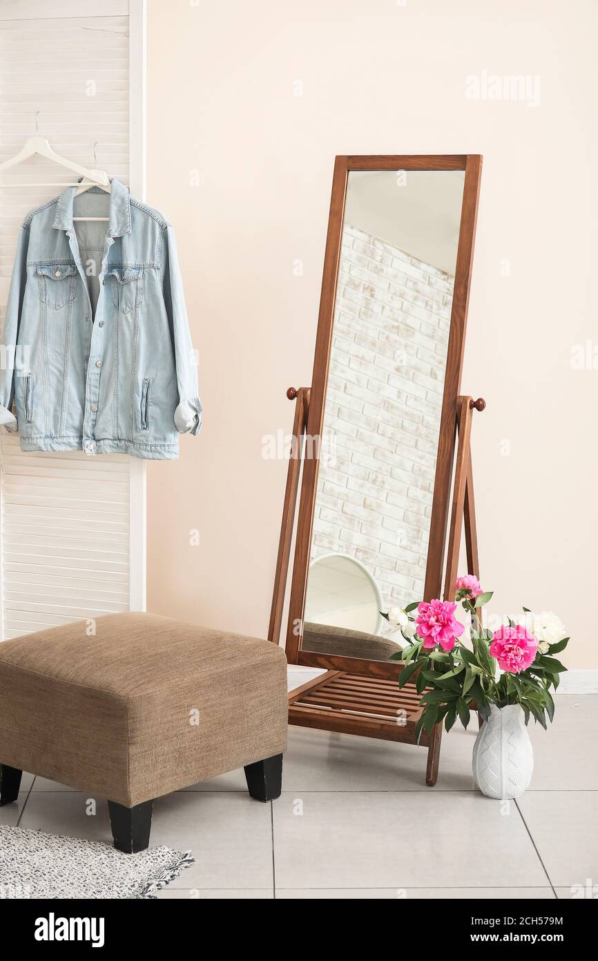 Big mirror with pouf near color wall in room Stock Photo - Alamy