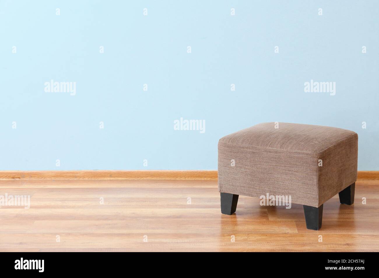 Stylish pouf near color wall Stock Photo - Alamy