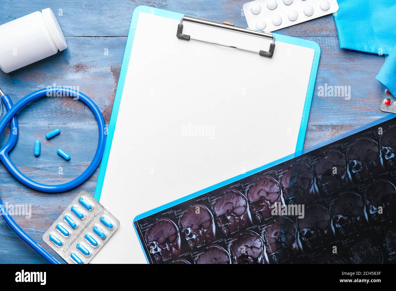 MRI scan of human head with clipboard, pills and stethoscope on table ...