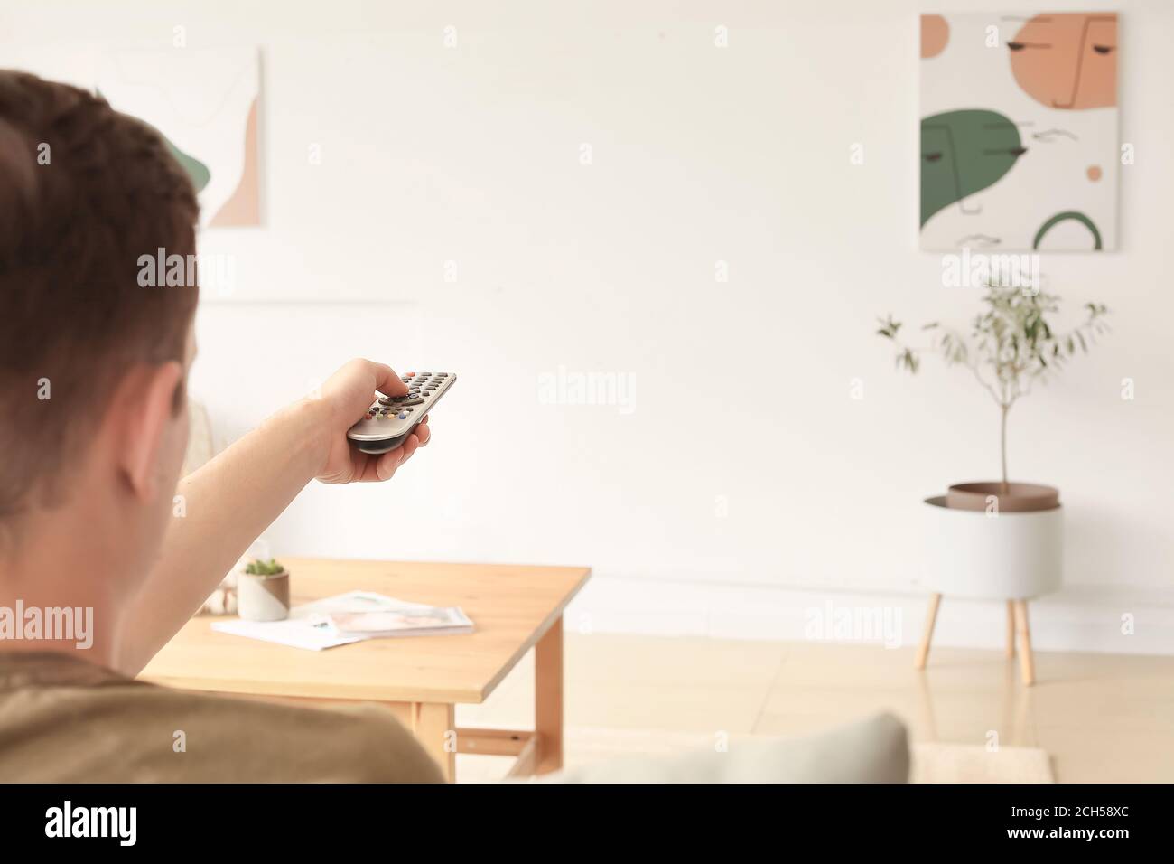 Young man with TV remote control at home Stock Photo - Alamy