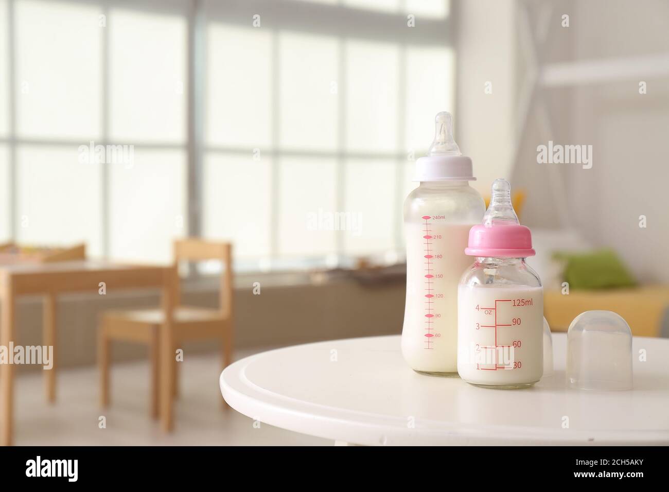 Bottles of milk for baby on table in room Stock Photo - Alamy