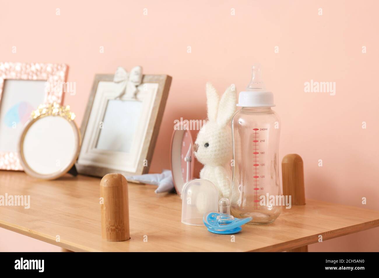 Bottle for baby with pacifier and toy on table in room Stock Photo - Alamy