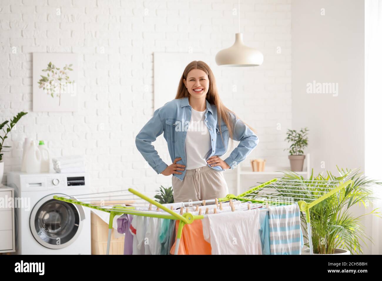 Woman hanging clean clothes on dryer in laundry room Stock Photo - Alamy