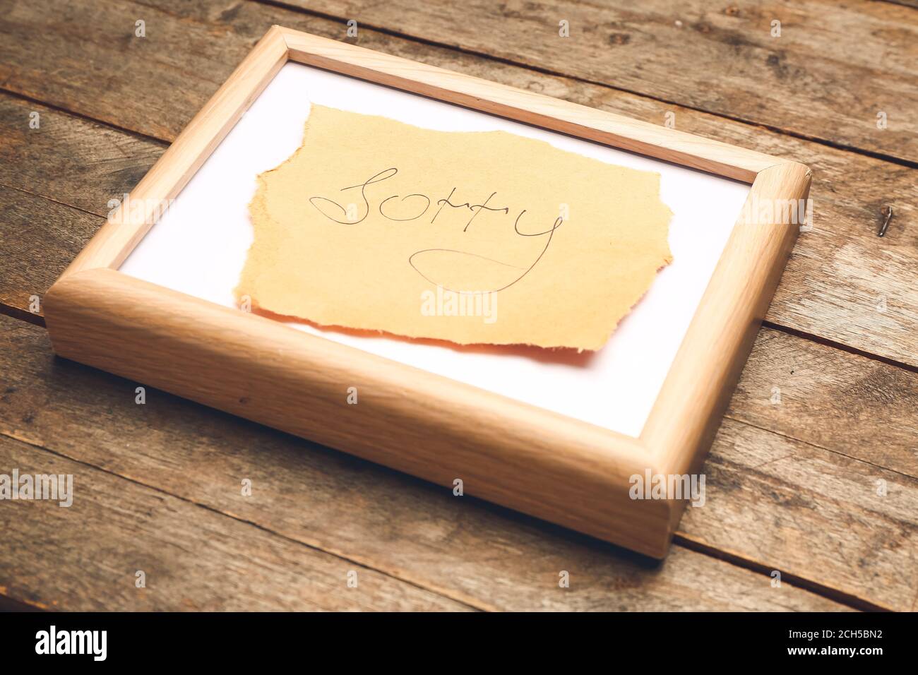 Photo frame and paper sheet with word SORRY on wooden background Stock ...
