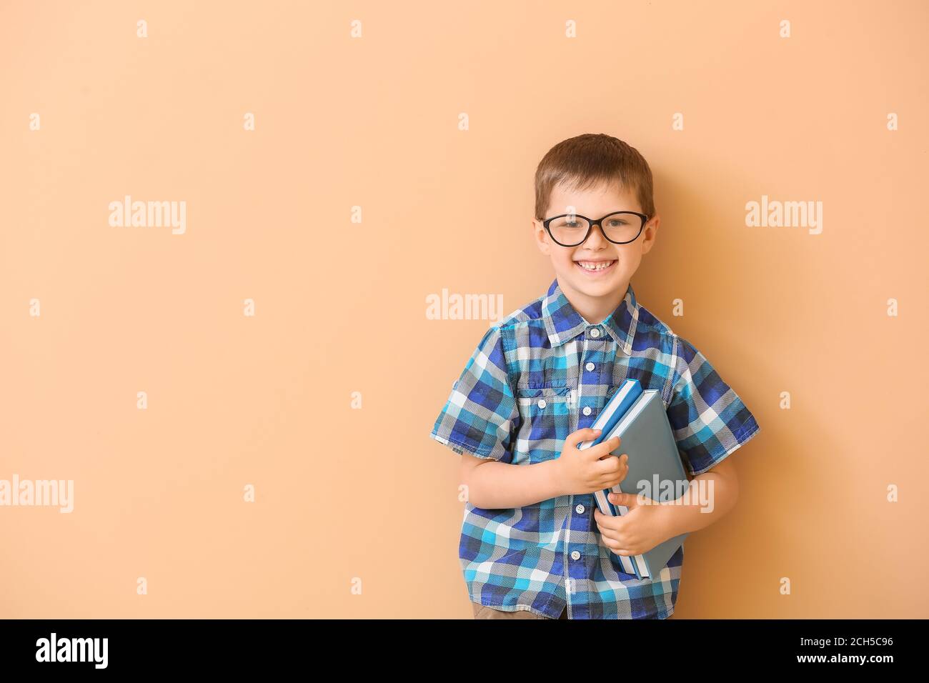 Cute little boy with books on color background Stock Photo - Alamy
