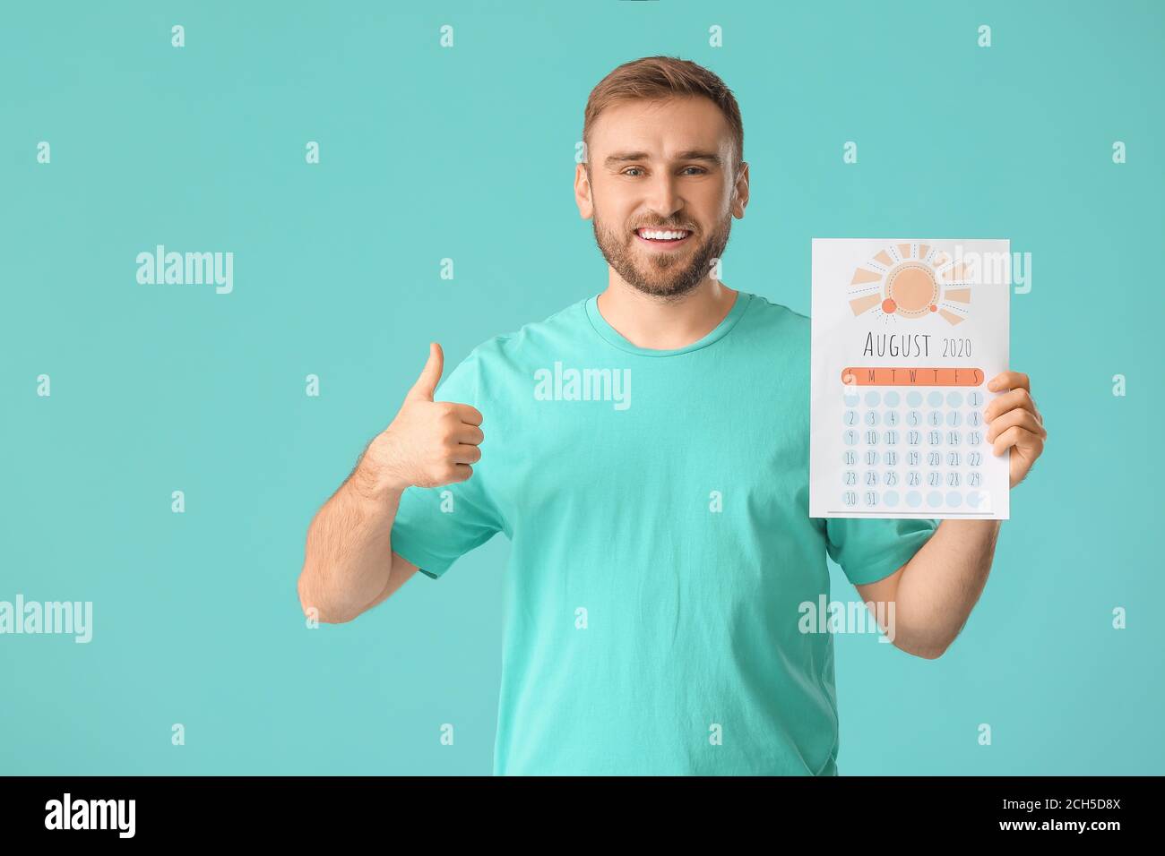Young man with calendar showing thumb-up gesture on color background ...