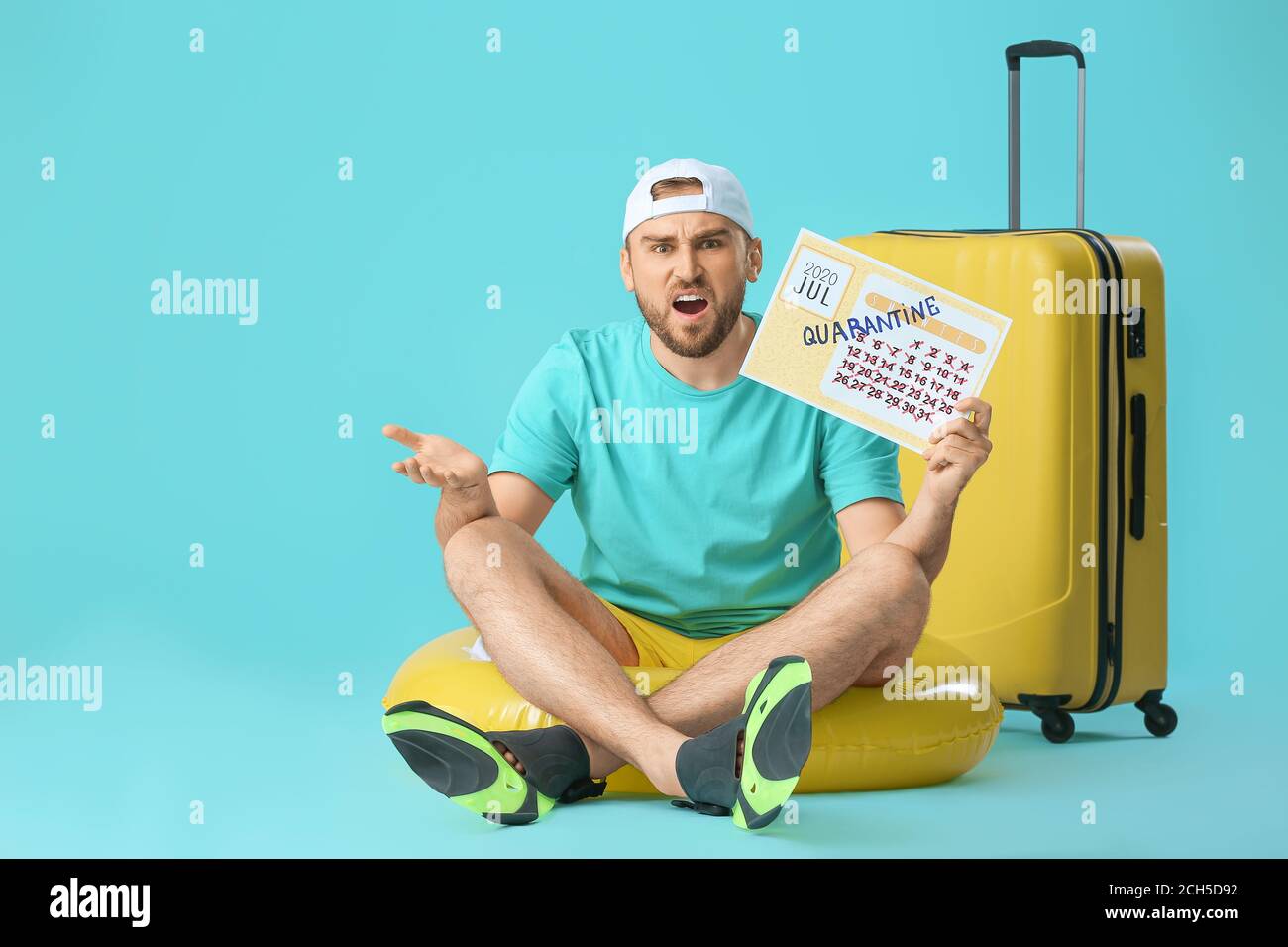Angry man holding calendar with written word QUARANTINE against color ...