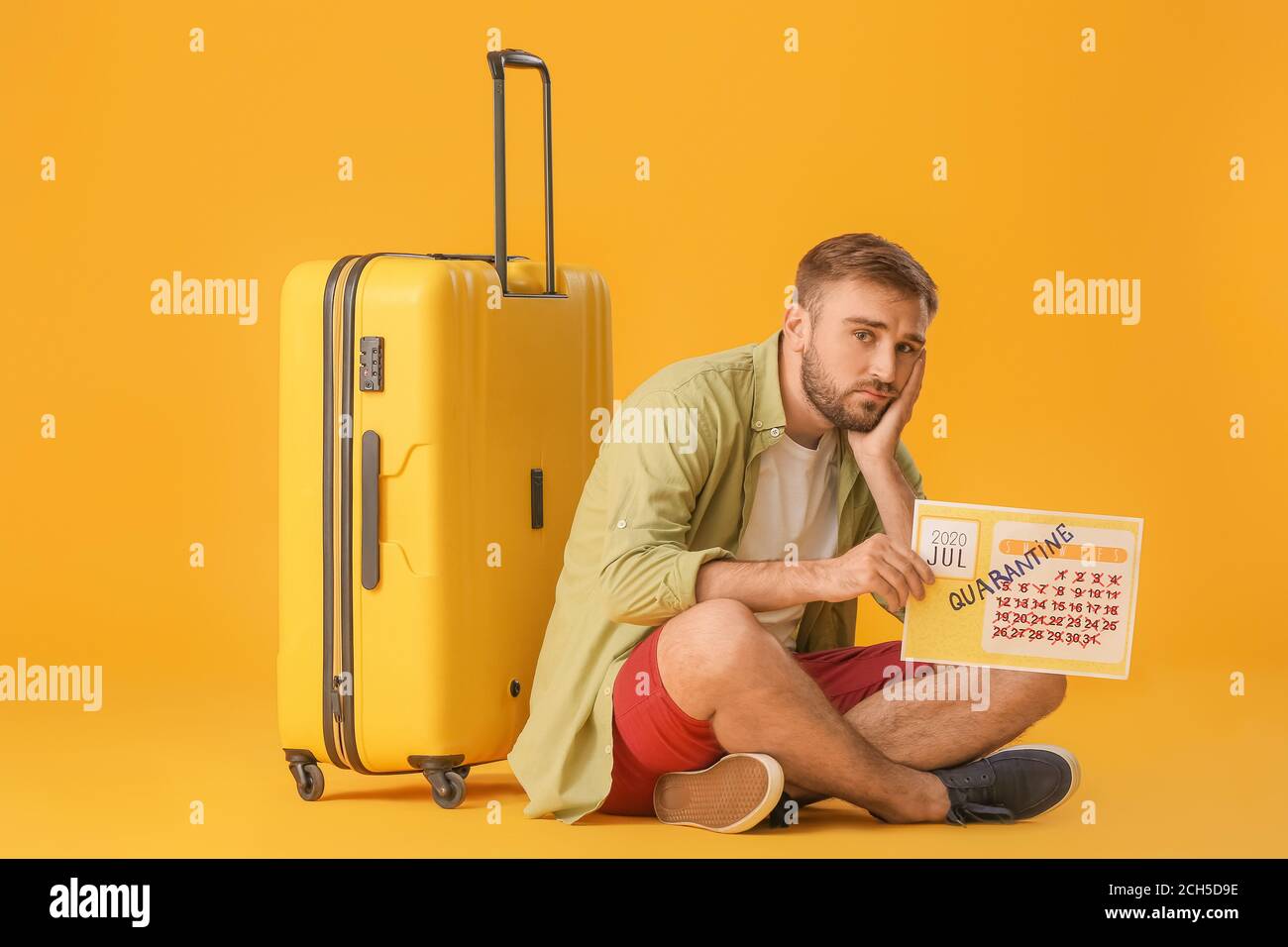 Sad man holding calendar with written word QUARANTINE against color ...