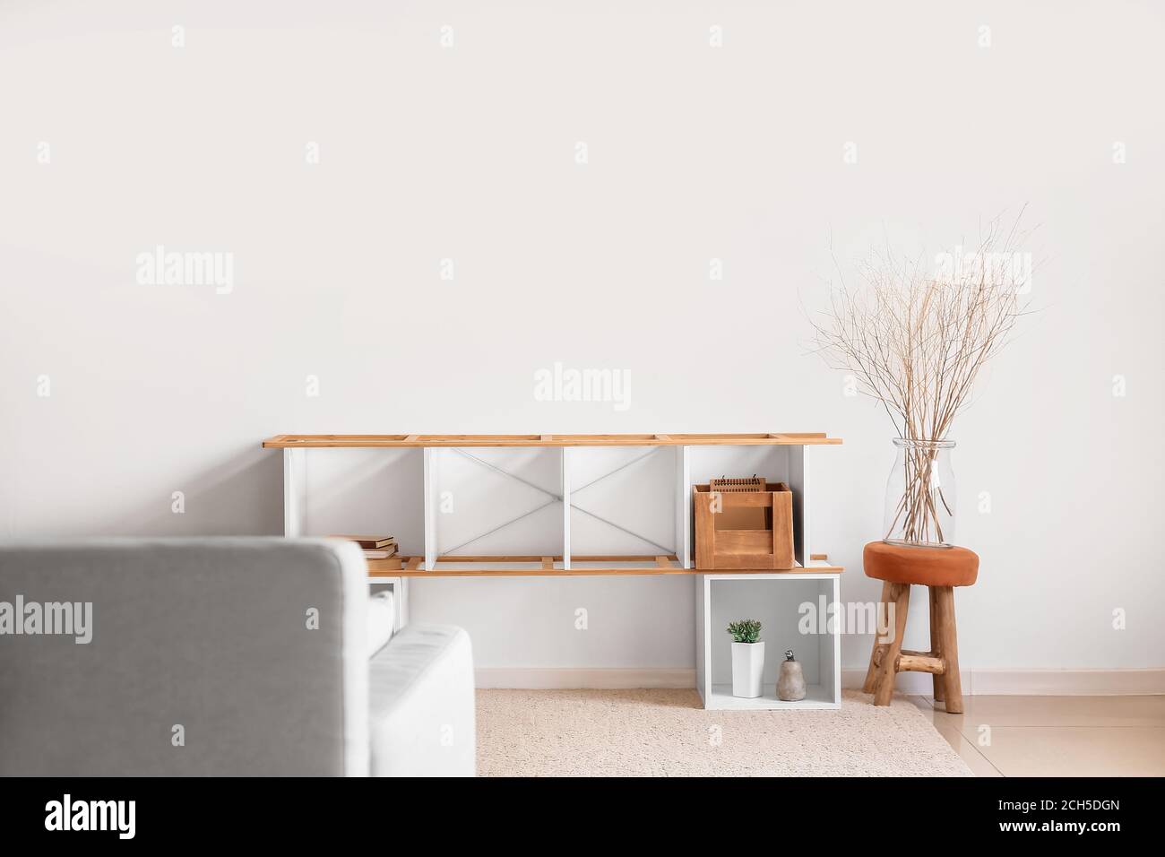 Stylish stand with decor near light wall in room Stock Photo - Alamy