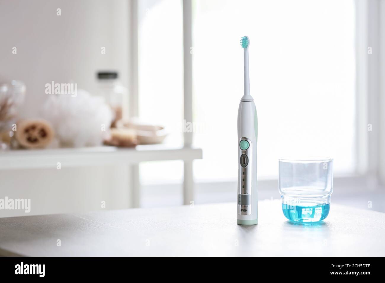 Electric tooth brush and mouth rinse on table in bathroom Stock Photo ...