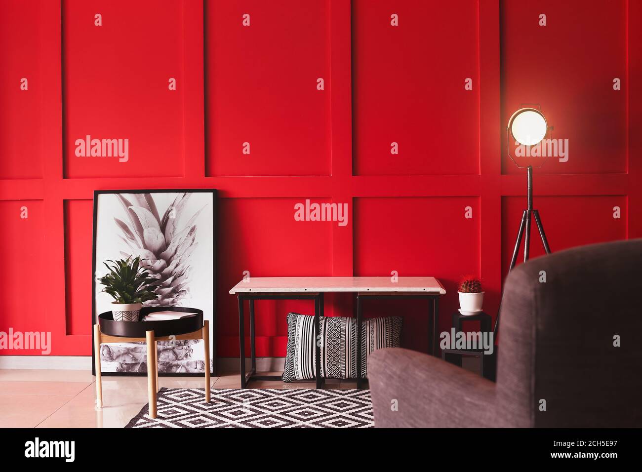 Stand with lamp and table near color wall in room Stock Photo - Alamy
