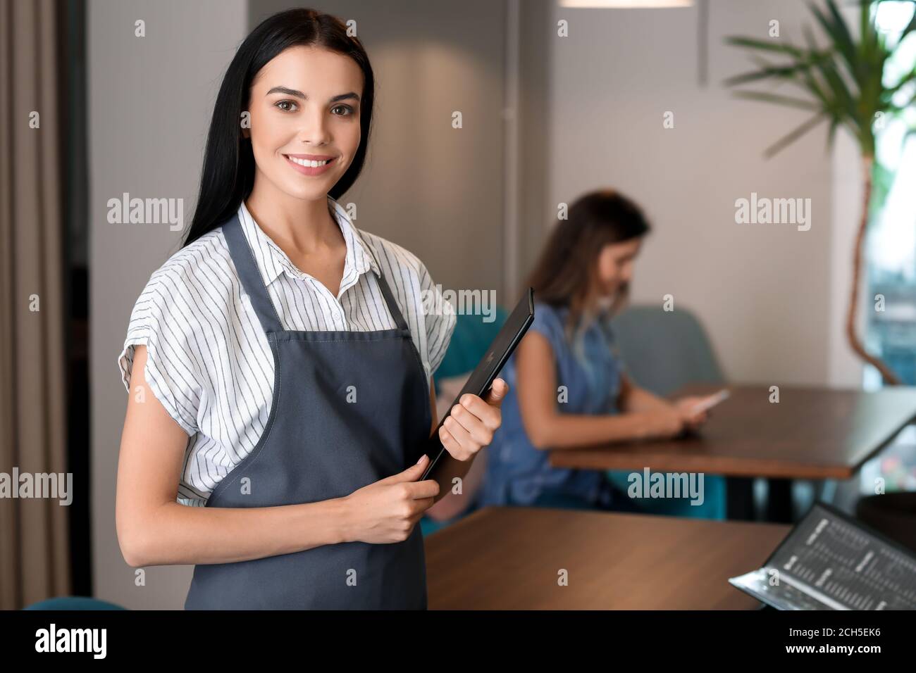 Young waitress with menu in restaurant Stock Photo - Alamy
