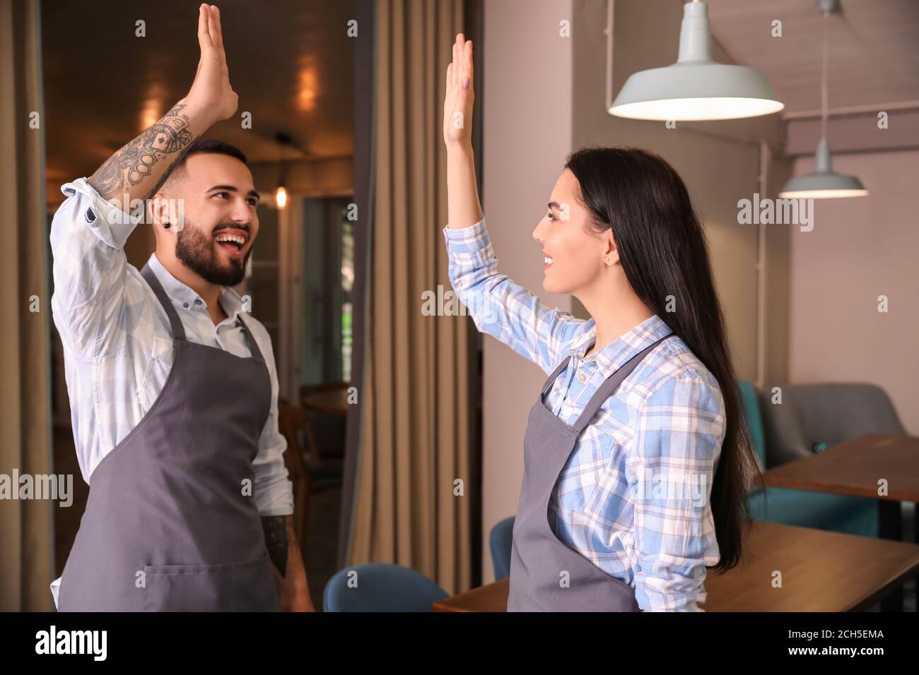 Young waiters giving high-five to each other in restaurant Stock Photo ...