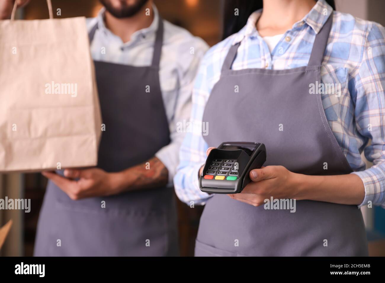 Young waiters with food for delivery and payment terminal in restaurant ...