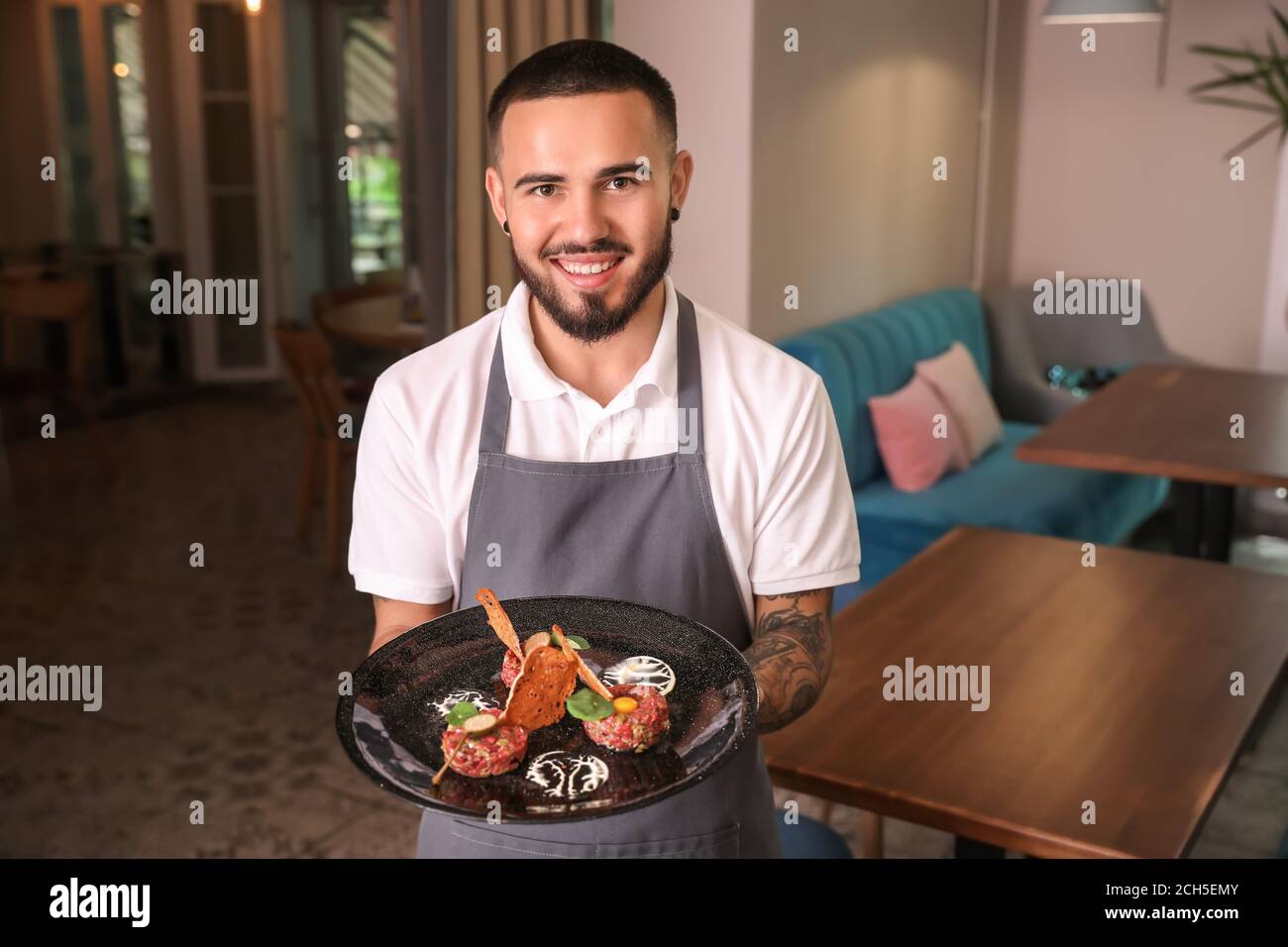 Young male waiter with dish in restaurant Stock Photo - Alamy