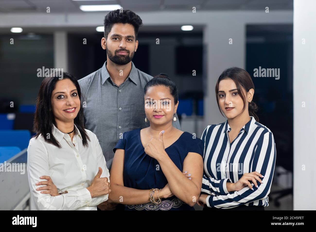 Four Indian office colleagues standing together with arms folded ...