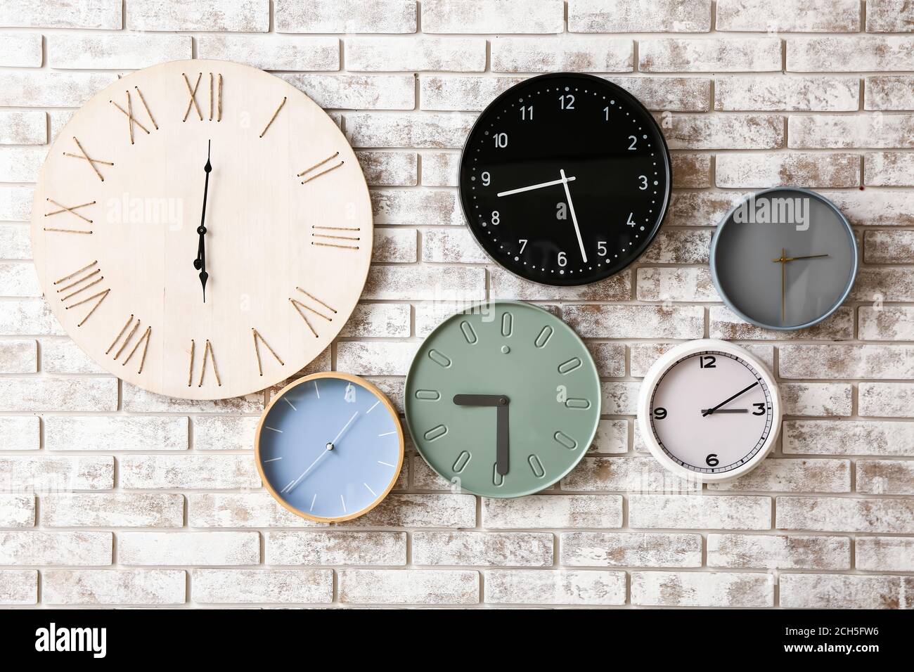 Different clocks on brick wall Stock Photo - Alamy