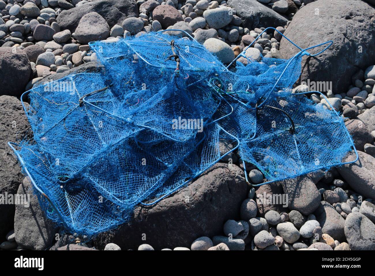 Damaged blue nets on grey rocky shore Stock Photo - Alamy
