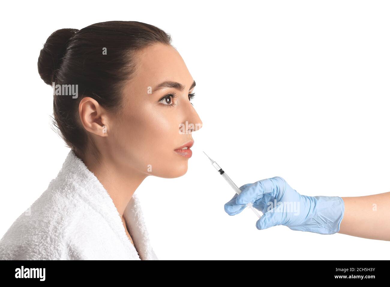 Beautiful young woman receiving injection of filler on white background ...