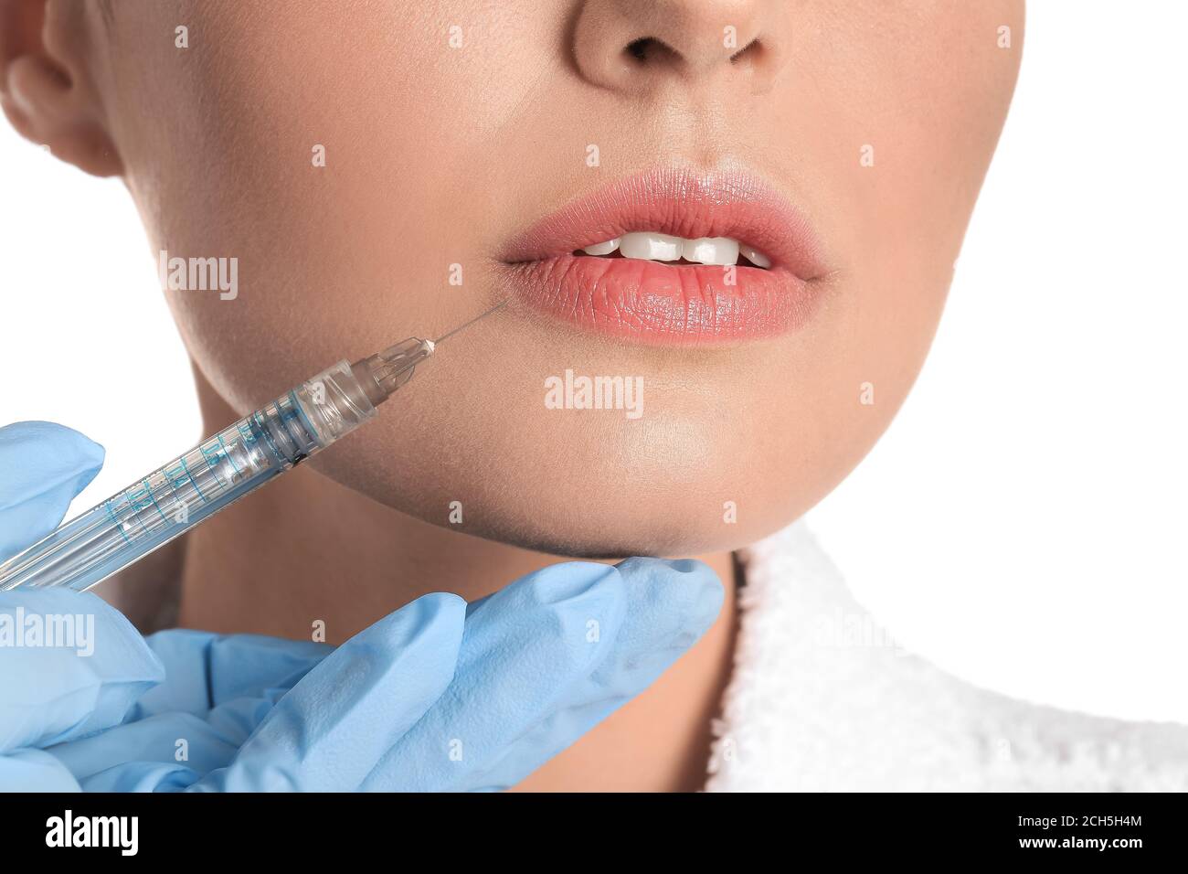 Beautiful young woman receiving injection of filler on white background ...