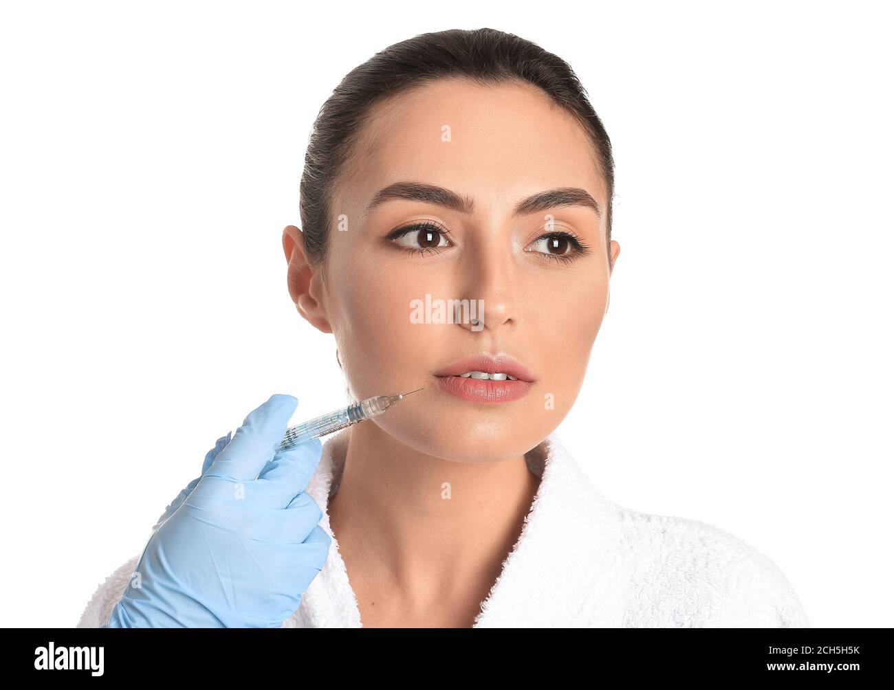 Beautiful young woman receiving injection of filler on white background ...