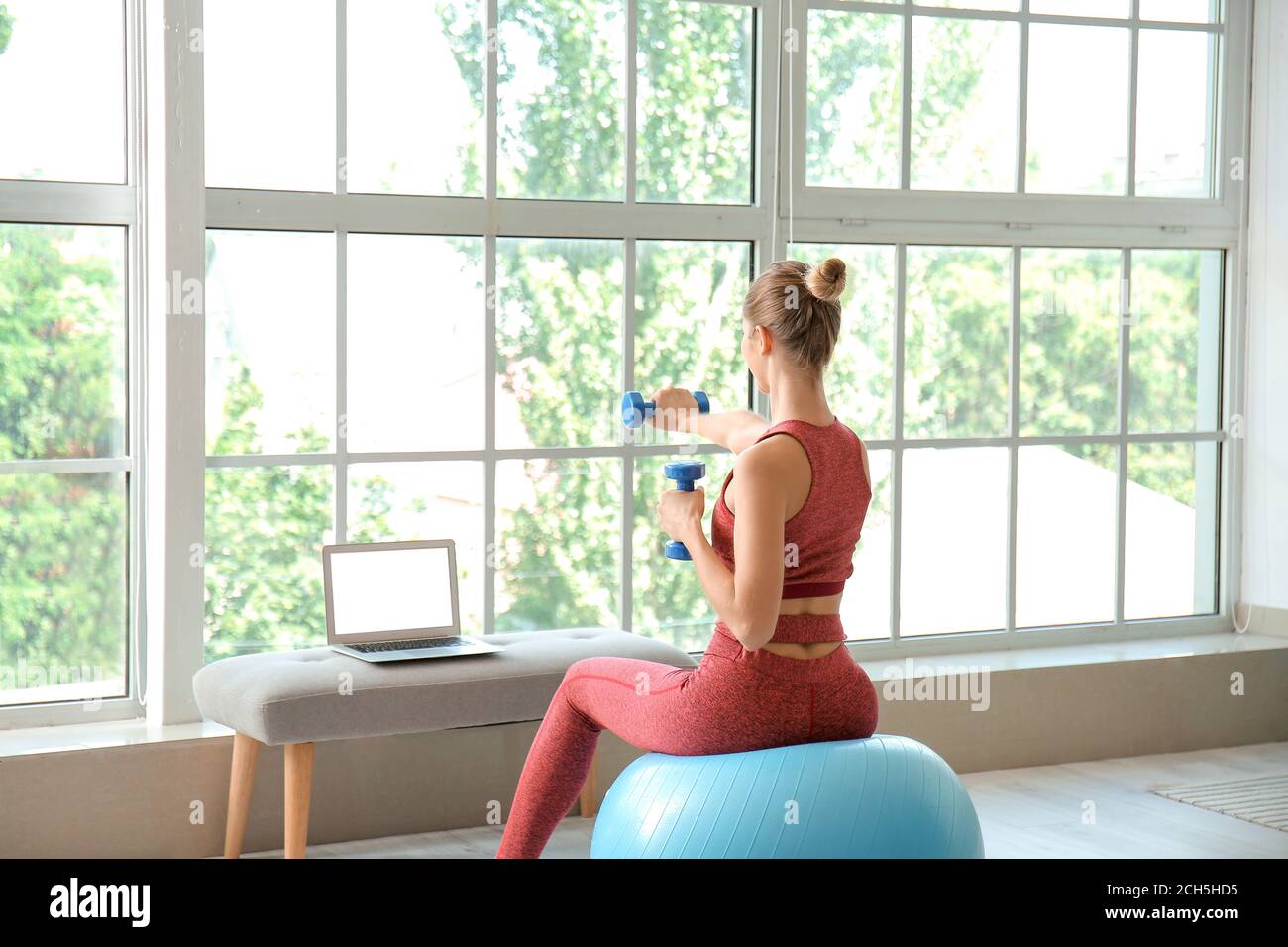 Sporty young woman with laptop training at home Stock Photo - Alamy